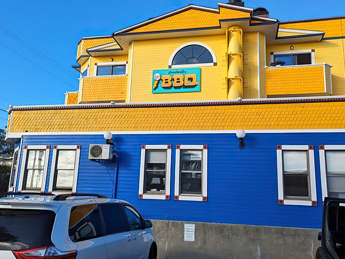 The sunshine-yellow and ocean-blue building stands like a beacon of barbecue hope on the coastline, promising smoky treasures within.