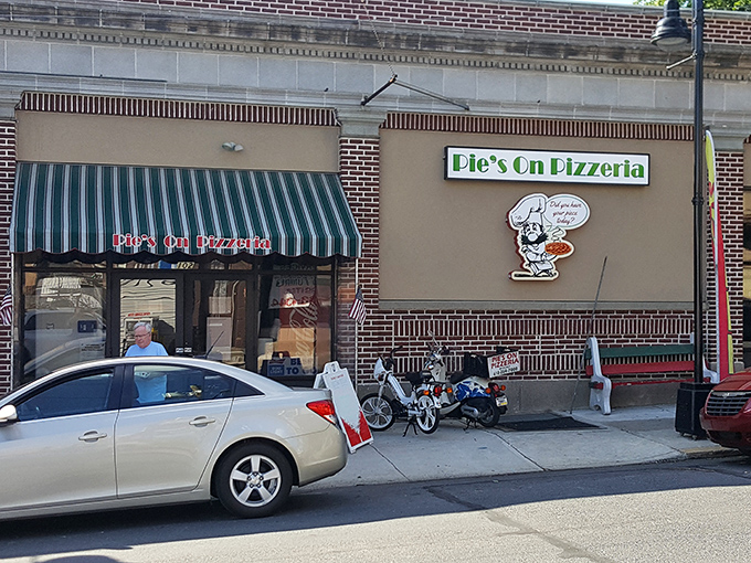 The green and white awning beckons like an old friend saying, "Hey, come get some pizza already!" Classic small-town charm with big pizza energy.