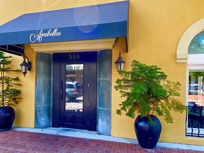 The golden façade and royal blue awning of Arabellas isn't just a restaurant entrance—it's a portal to Italy hiding in plain sight on Winter Haven's brick-lined streets.