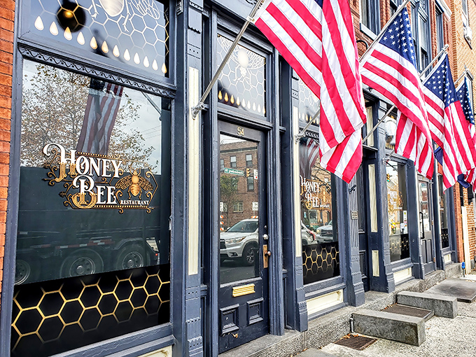 The historic brick façade of Honey Bee Restaurant stands proudly in Gettysburg, its honeycomb-patterned windows and American flags promising both comfort and patriotism inside.