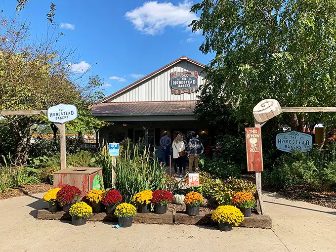 The welcoming facade of The Homestead Bakery, where colorful mums and rustic signage promise sweet treasures within. A slice of Amish country heaven awaits.