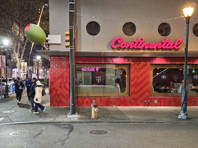 The Continental's iconic red façade with porthole windows stands like a retro spaceship that landed in Rittenhouse Square, promising culinary adventures within.