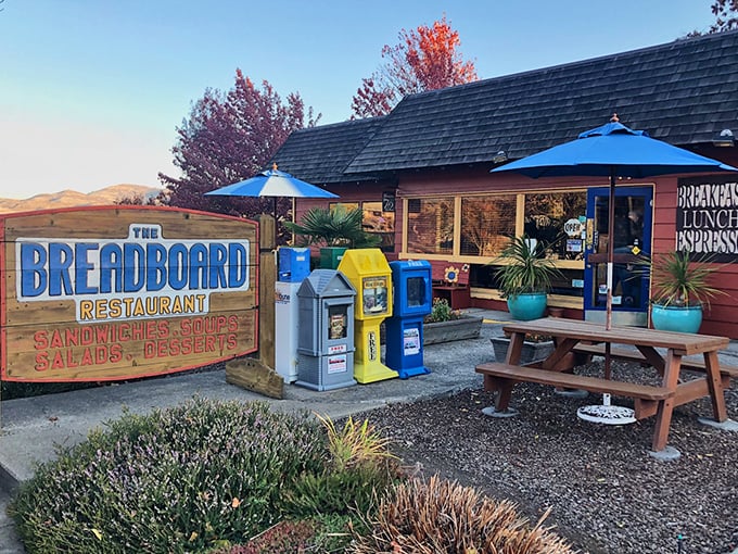 The rustic cabin exterior of The Breadboard promises comfort food nirvana. That red-checkered tablecloth isn't just decoration—it's foreshadowing.
