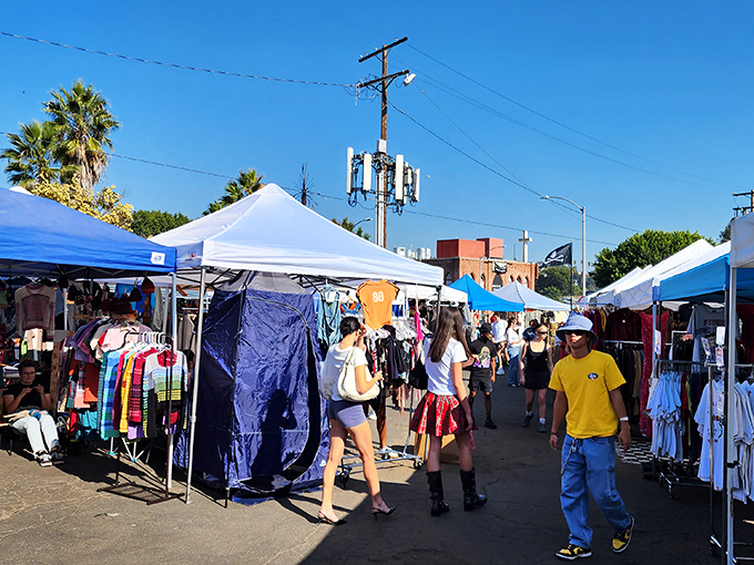 White canopies stretch into the distance like a modern-day bazaar, where treasure hunters navigate the narrow pathways between vendors under classic LA palm trees.