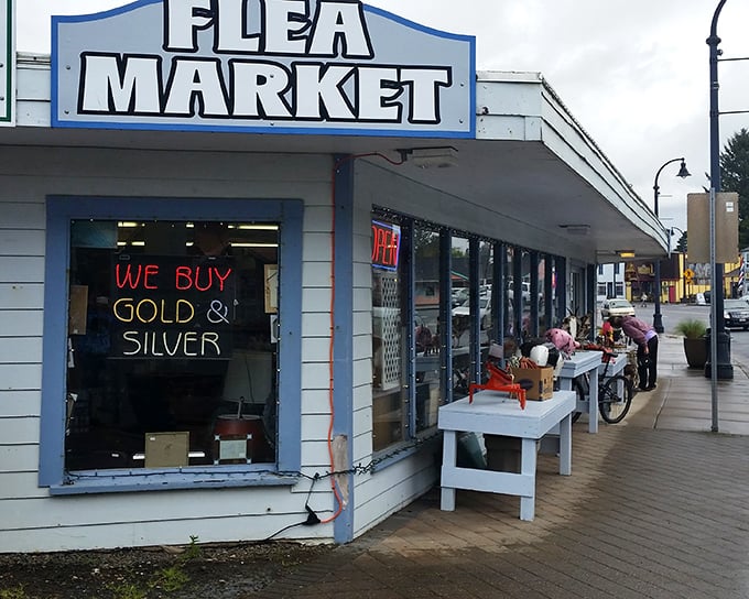 The unassuming blue-trimmed exterior of Waldport Flea Market beckons with promises of hidden treasures and the glow of that classic "WE BUY GOLD & SILVER" neon sign.