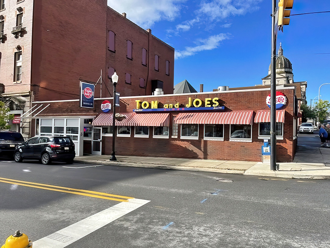 The iconic red-and-white awnings of Tom & Joe's stand proudly against Altoona's skyline, with the courthouse dome creating a perfect backdrop for this beloved diner.