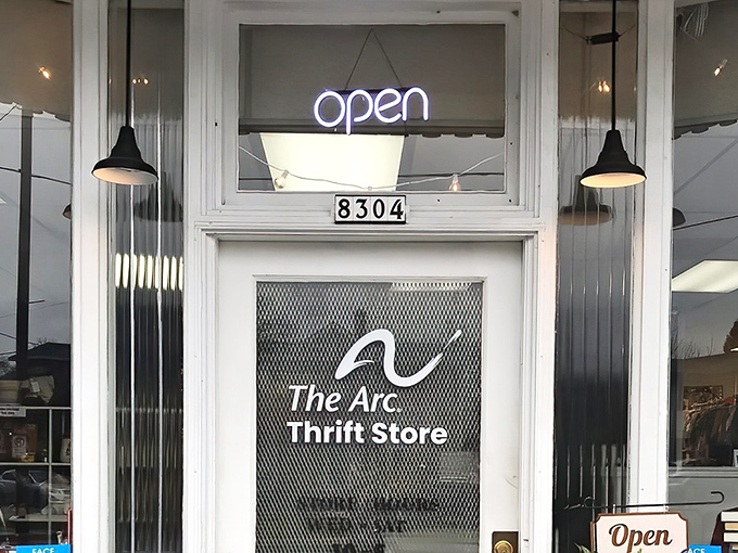 The welcoming storefront of The Arc Thrift Store beckons with its glowing neon sign—like a lighthouse guiding bargain hunters to treasure-filled shores.