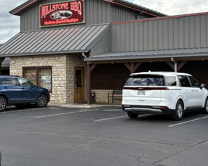 The stone-and-metal exterior of Millstone BBQ stands like a temple to smoked meat devotion, promising delicious treasures within.