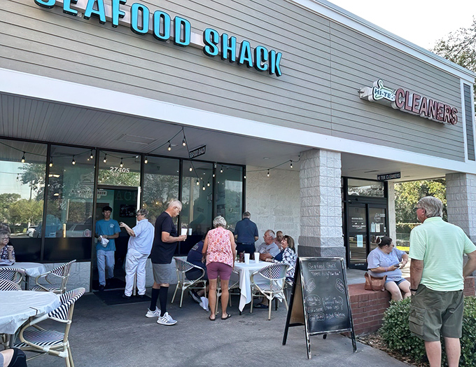 The bright turquoise "SEAFOOD SHACK" sign beckons like a coastal lighthouse, promising maritime treasures within. Those outdoor tables aren't just furniture—they're stages for impending seafood euphoria.