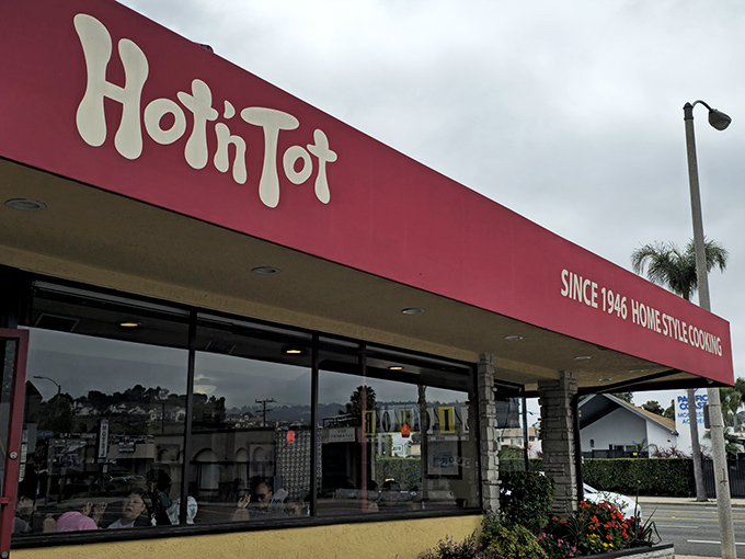 The iconic red signage of Hot 'n Tot stands as a beacon of culinary consistency on Pacific Coast Highway, promising homestyle comfort since 1946.