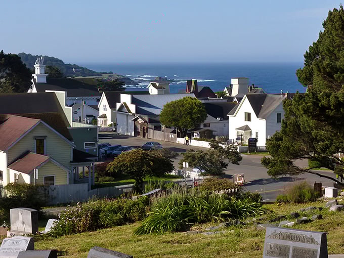 Mendocino perches on dramatic cliffs like nature's balcony, with white buildings peeking through trees above the rugged coastline.