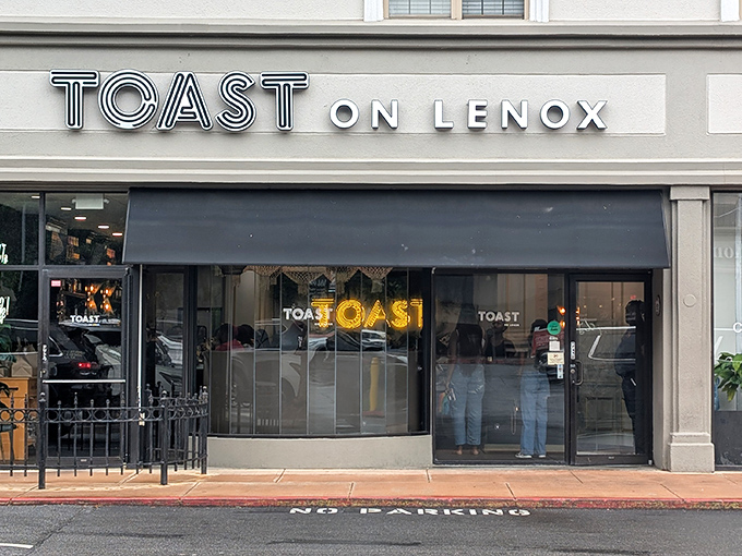 The sleek exterior of Toast on Lenox beckons with understated confidence, its black awning and clean signage promising culinary delights within Atlanta's vibrant Lenox neighborhood.
