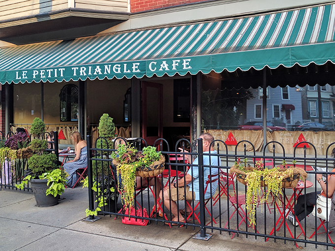 The charming brick facade of Le Petit Triangle Cafe beckons with its distinctive yellow awning and wrought-iron fence—a little slice of Paris on a Cleveland corner.