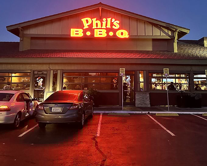 The neon glow of Phil's BBQ sign isn't just illumination—it's a beacon calling hungry souls home to barbecue paradise after sunset.