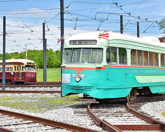 A turquoise PCC streetcar proudly displays its "14 Colorado" destination sign, while a maroon trolley waits its turn in the background. Time travel on rails!