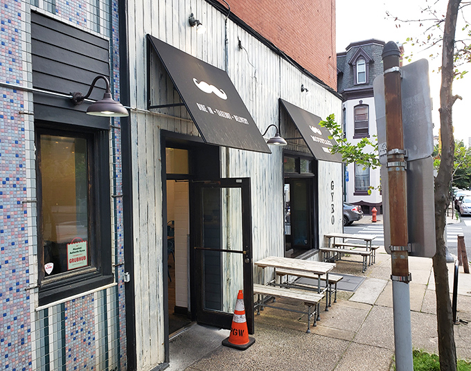 The unassuming storefront with its weathered wood and dapper mustache logo promises authentic Greek delights inside this Philadelphia corner treasure.
