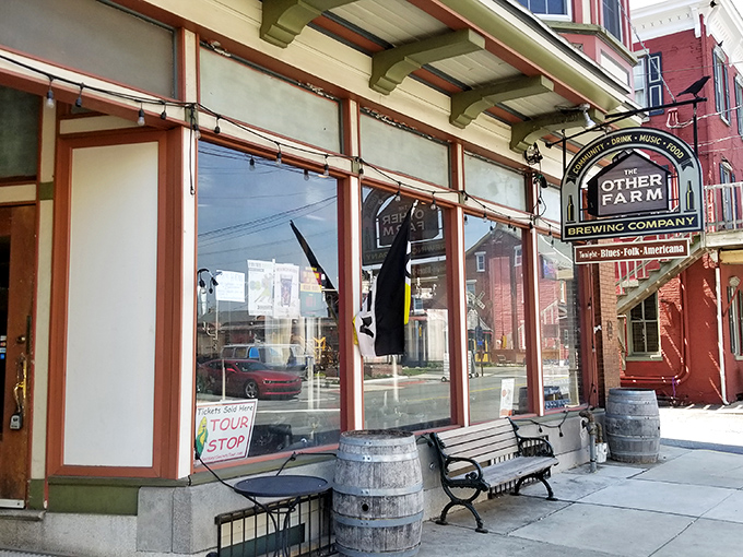 The charming storefront of The Other Farm beckons with its classic Pennsylvania brick facade, wooden bench, and barrel planters—small-town Americana at its most inviting.