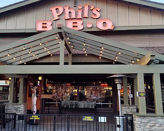 The neon glow of Phil's BBQ sign isn't just illumination—it's a beacon calling hungry souls home to barbecue paradise after sunset.