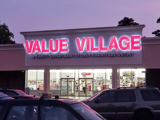 The neon-red Value Village sign glows like a beacon for bargain hunters, promising treasures within its walls as dusk settles over Decatur. 