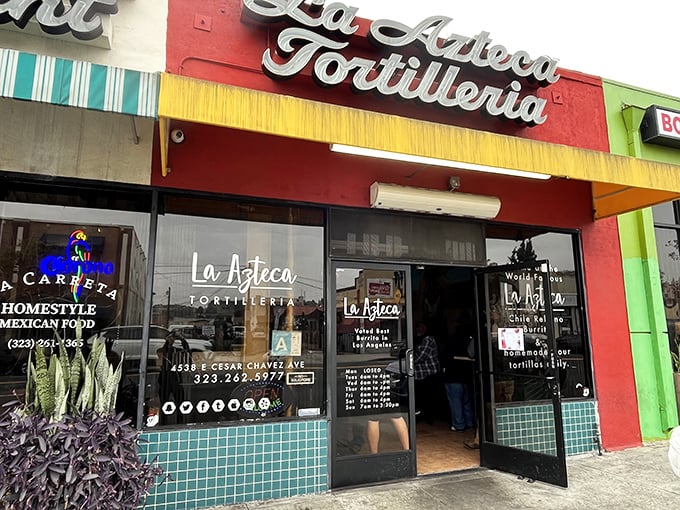 The vibrant red and yellow façade of La Azteca Tortilleria stands like a beacon of culinary promise on Cesar Chavez Avenue.
