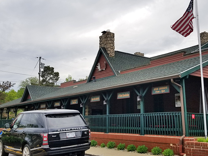 The rustic charm of Timber Lodge beckons from the roadside, its log cabin exterior and American flag promising a quintessentially Midwestern steakhouse experience.