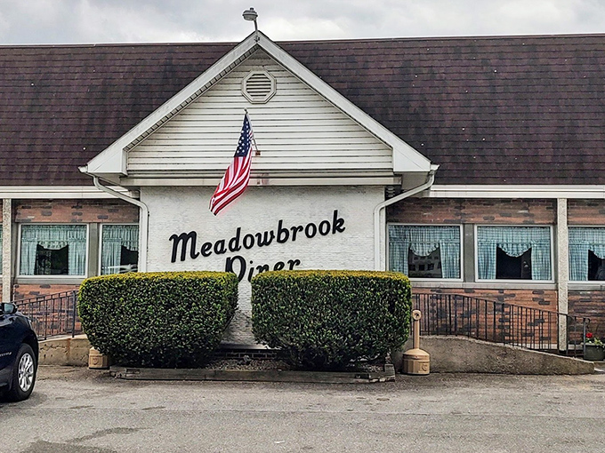 The classic American flag above Meadowbrook Diner isn't just decoration—it's a promise that inside awaits the kind of breakfast that made this country great.