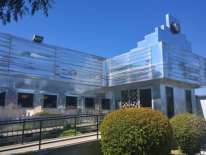 The gleaming stainless steel exterior of Dimples Diner shines like a beacon of hope for hungry travelers. Mid-century modern meets comfort food paradise.