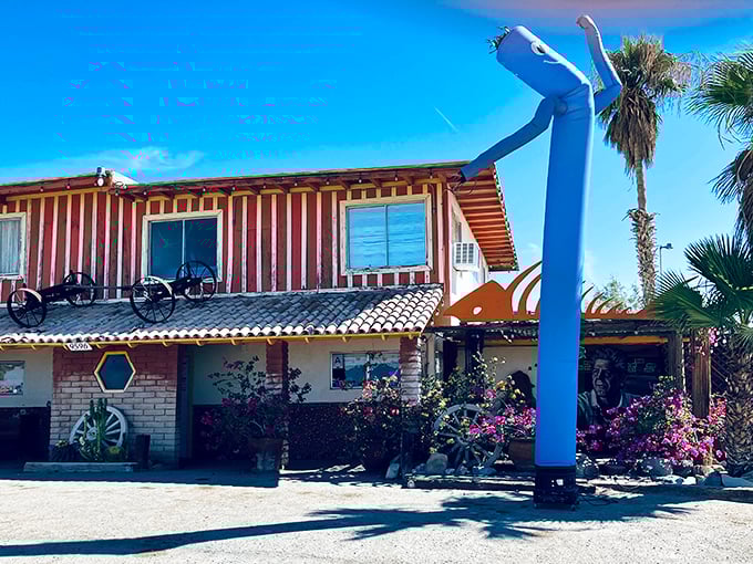 The Ski Inn's distinctive exterior stands like a mirage in the desert, complete with that quirky blue inflatable figure welcoming hungry travelers.