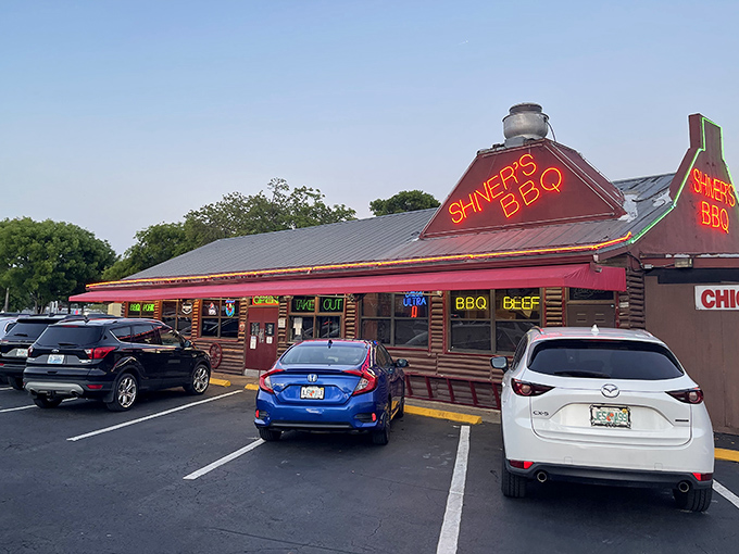 That neon glow isn't just for show—it's a barbecue beacon calling hungry souls to this log cabin sanctuary where smoke signals promise delicious things ahead.