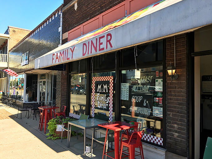 The unassuming storefront of M & M Family Diner beckons with its classic red chairs and checkered window display. Small-town charm at its finest.