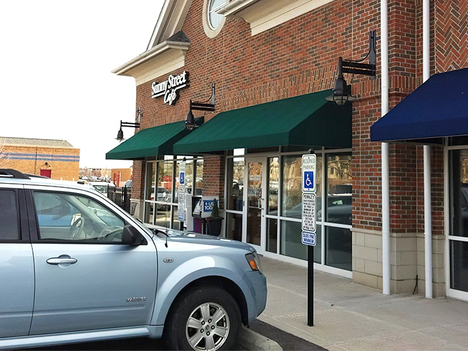 The unassuming brick exterior of Sunny Street Café, where culinary magic happens behind those modest green awnings. Breakfast nirvana awaits!
