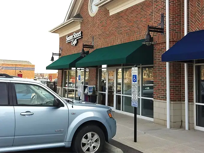 The unassuming brick exterior of Sunny Street Café, where culinary magic happens behind those modest green awnings. Breakfast nirvana awaits!