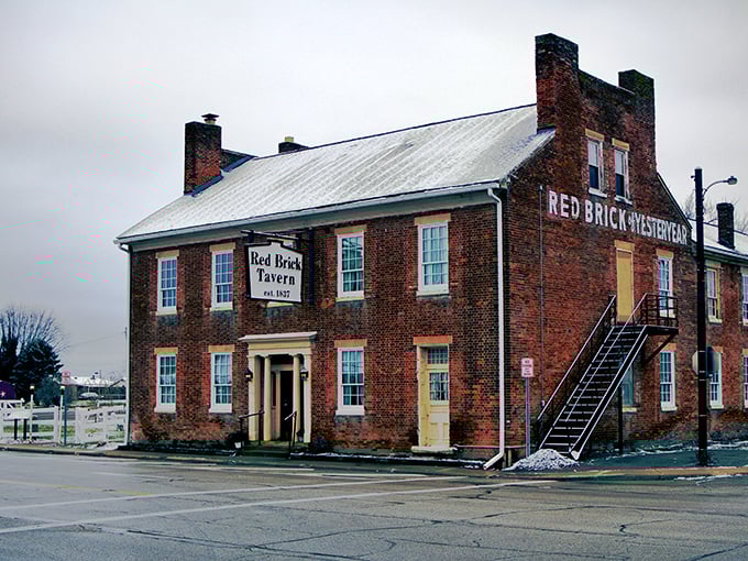 The historic Red Brick Tavern stands proudly along Route 40, its weathered facade a testament to nearly two centuries of serving hungry travelers since 1837.