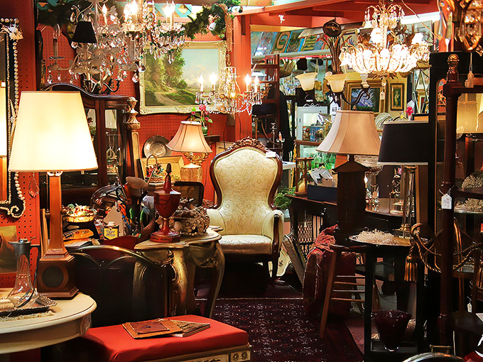 Lampshades and chandeliers create a warm glow over this elegant booth, where Victorian chairs wait patiently for their next living room to grace.