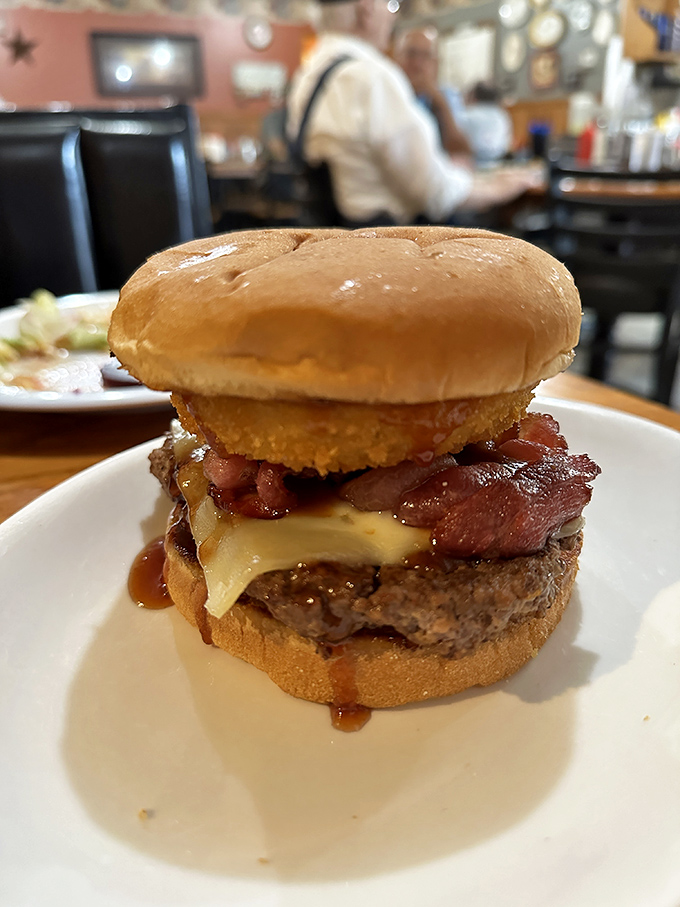 Not all heroes wear capes—some wear bacon, cheese, and what appears to be an onion ring crown. This burger doesn't just satisfy hunger—it conquers it.