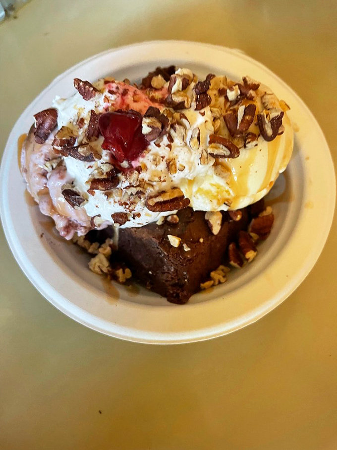 This isn't just a brownie sundae—it's architecture. The pecans add texture while the whipped cream crowns this temple of indulgence.