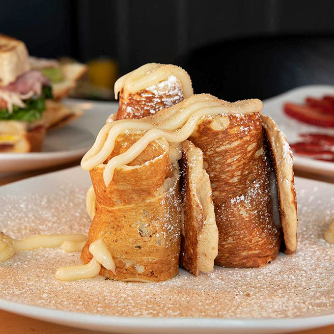 Cinnamon roll pancakes, dusted with sweetness and drizzled in luscious cream cheese glaze — a dreamy treat perfect any time of day.