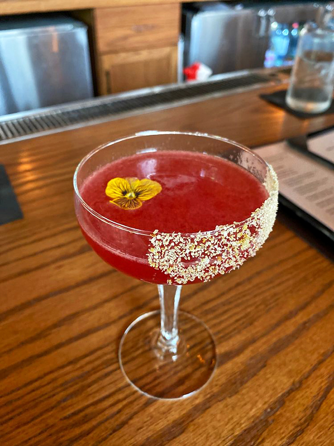 This isn't just a cocktail—it's liquid art with that edible flower floating like a tiny celebration on top.