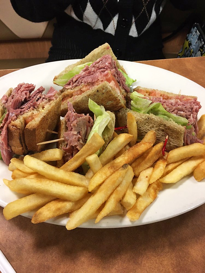 A corned beef club sandwich stacked so high it requires strategic planning before the first bite.