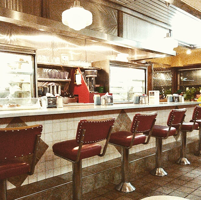 The counter seats—where solo diners become part of the diner's story, watching short-order ballet performed with spatulas and sizzling grills.