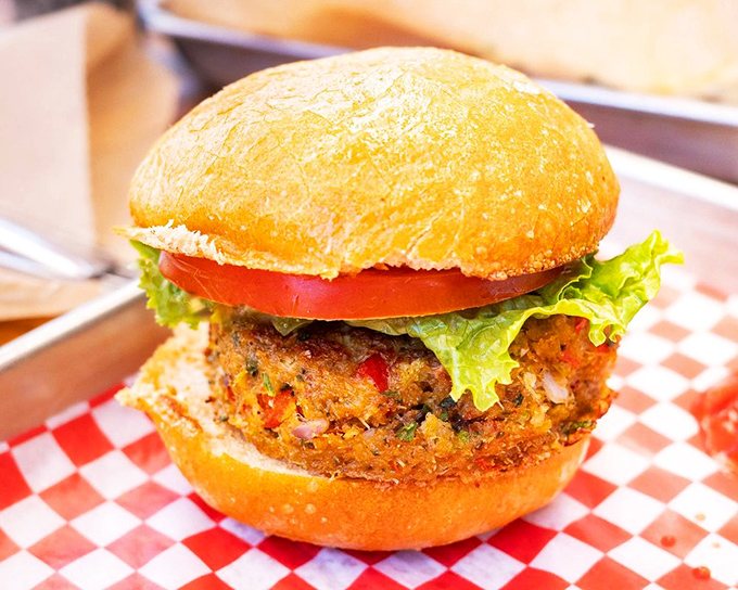 This isn't just a sandwich—it's seafood architecture. The golden-brown crab cake nestled between fresh veggies and a pillowy bun is comfort food elevated.