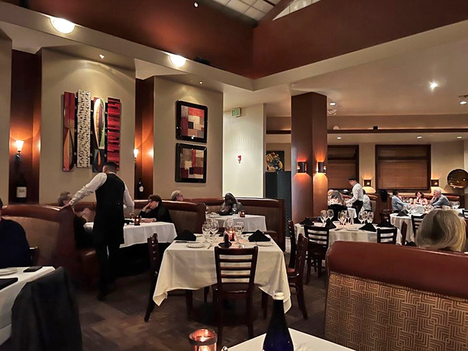 This upscale dining room offers a warm, intimate atmosphere with elegant table settings, modern art décor, and attentive service—ideal for a refined evening out.