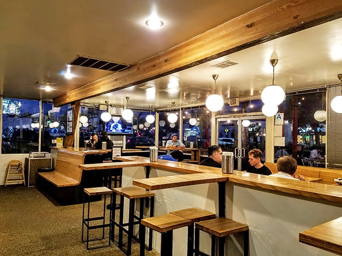 The evening ambiance transforms The Oinkster into a cozy dinner spot where wooden booths cradle conversations as comfortably as they do customers.