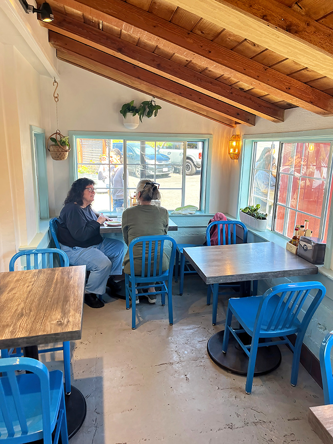 The blue chairs add a pop of coastal color in this sunny corner, where diners linger over meals worth savoring rather than rushing back to reality.