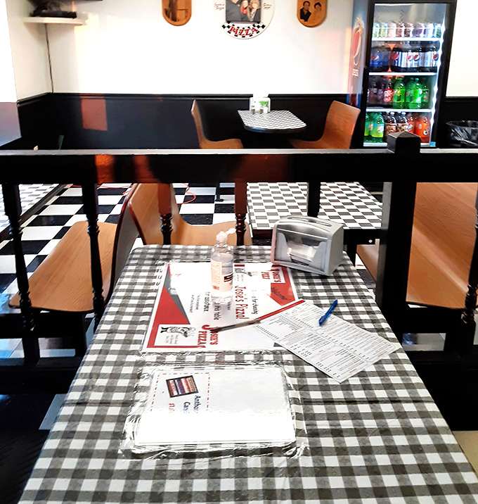 Classic black and white checkered floors meet cozy booths—the timeless pizzeria aesthetic that instantly makes you feel like a regular.