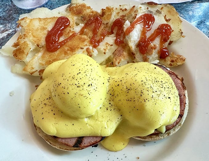 Eggs Benedict done right – a silky hollandaise blanket tucked over Canadian bacon and perfectly poached eggs, with home fries that deserve their own fan club.