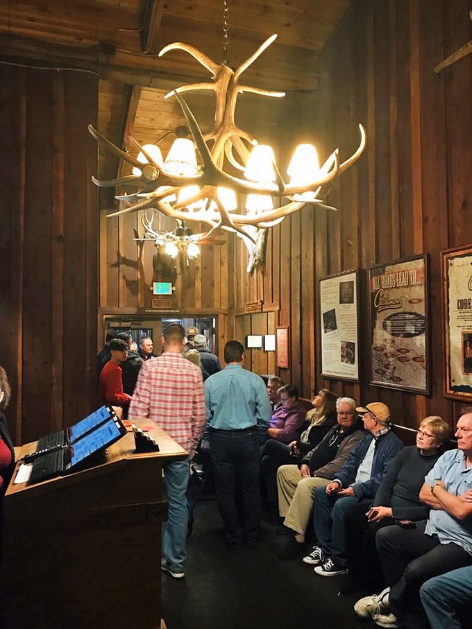 The waiting area under antler chandeliers isn't just where you stand—it's where anticipation builds and the aroma of grilled perfection teases what's to come.