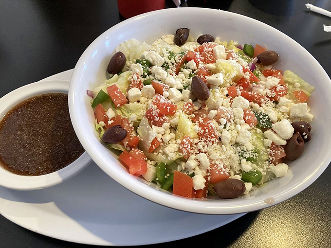 This Greek salad offers a refreshing counterpoint to diner indulgences – crisp vegetables, briny olives, and feta create Mediterranean vacation vibes.