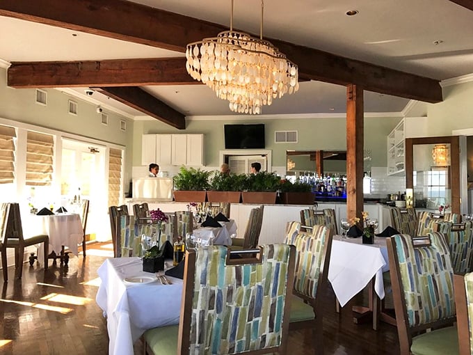 Sunlight streams through windows illuminating coastal-hued chairs and crisp white tablecloths—the stage is set for culinary magic to unfold.