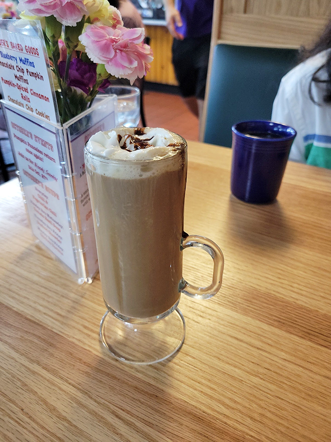 Coffee elevated to dessert status—whipped cream melting into a caramel embrace while fresh flowers remind you to stop and smell the caffeine.